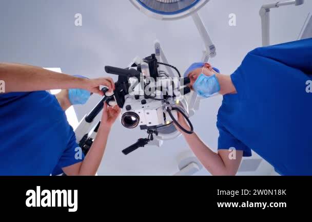 Two surgeons customizes modern microscope before the operation ...