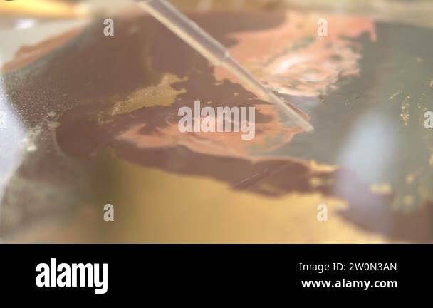 a drop of alcohol drops from a pipette onto a canvas with acrylic paint ...