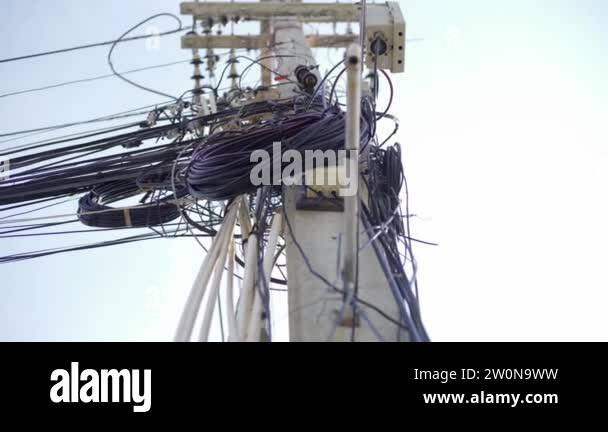 Messy wires attached to the electric pole, the chaos of cables and ...