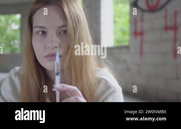 Woman shake off heroin from a syringe preparing to make injection close ...