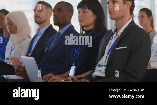 Close up side view of a diverse audience at a business seminar raising ...