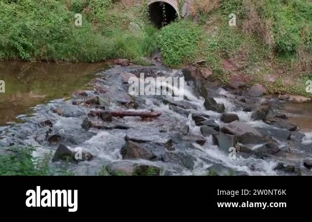 Sewage pipe outflow into river, water pollution and ecology concept ...