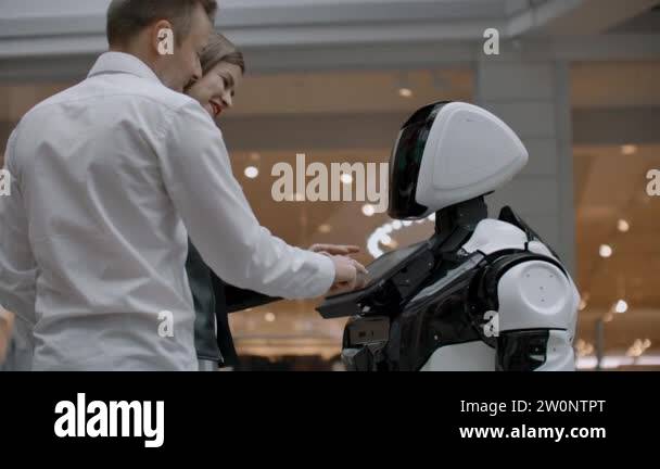 Two people a man and a woman communicate with a robot. Press the robot ...