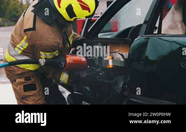 Fireman cutting car door open at scene of car accident. Slow motion ...