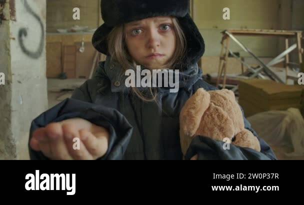 Little homeless Caucasian girl in dirty winter clothes holding the ...