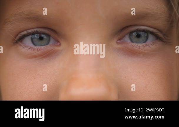 Blue eyes of beautiful small girl blinking and looking into camera with ...