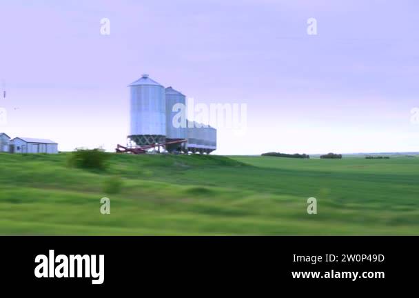 A drive by along recently planted fields with large metal grain silos ...