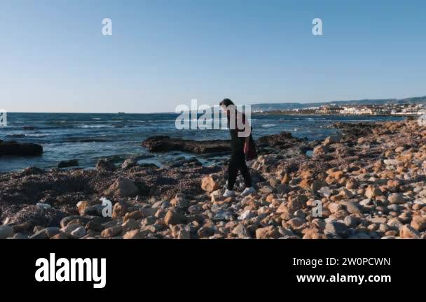Lonely melancholy young woman walking on empty pebble beach. Young ...