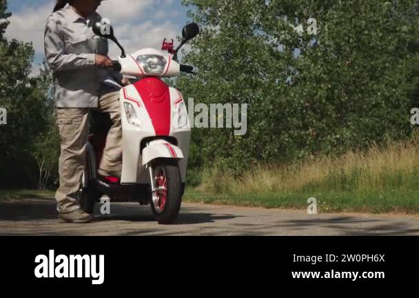 Disabled person driving a motorized mobility scooter for elderly and or ...