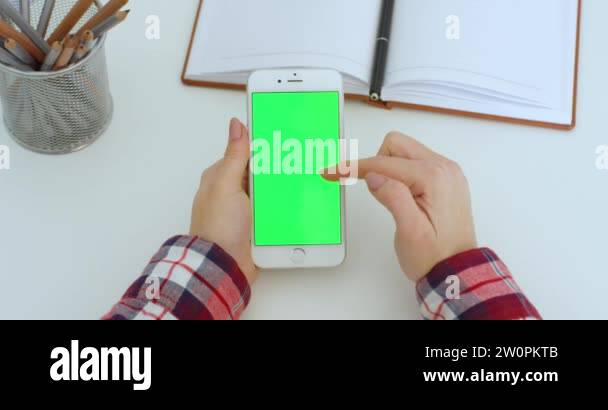 White vertical smartphone with green screen in hands of Caucasian woman ...