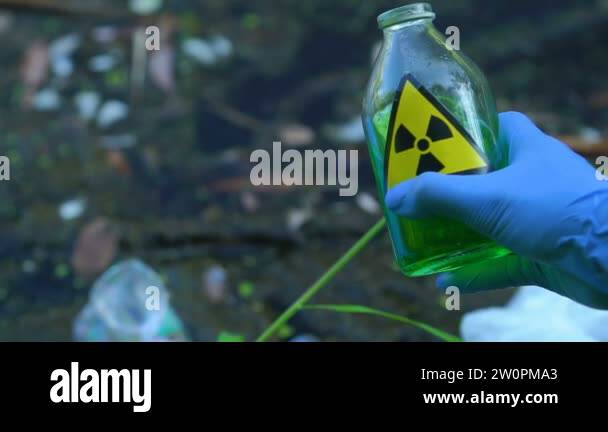 Hand in glove pouring radioactive liquid on landfill, ecological hazard ...