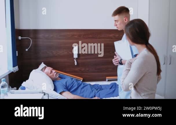 Sick old man in the hospital. Young doctor talking to the male patient ...