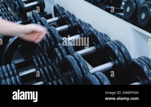 Man hands taking bodybuilding dumbbells in gym club. Closeu hands ...