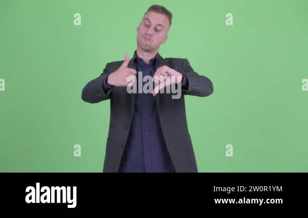 Confused businessman in suit choosing between thumbs up and thumbs down ...