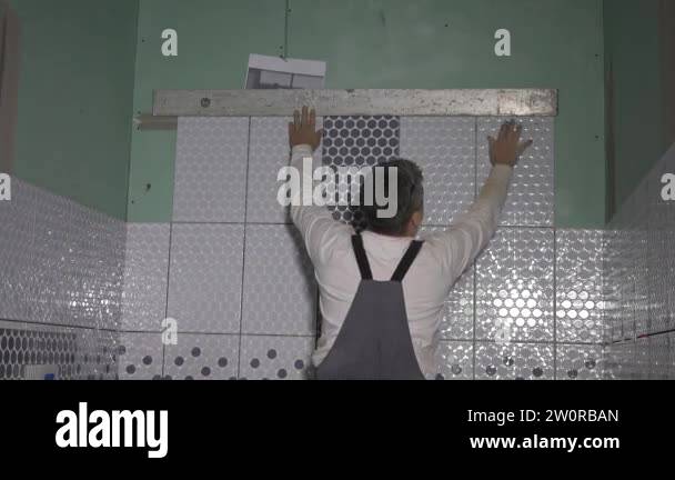 Construction master man check level of new wall tiles with leveling ...