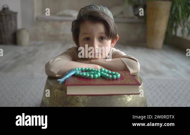 Cute little boy with koran book in prayer hat, arabic clothes and rosary beads, prophet Muhammad ...