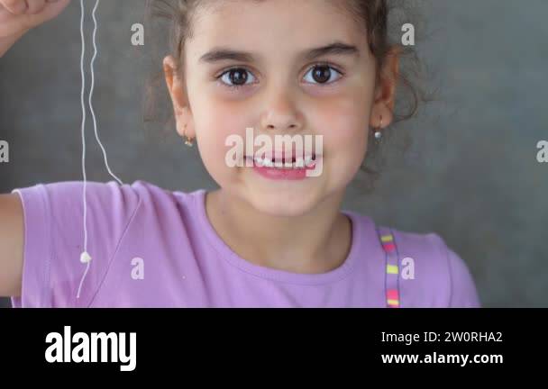 Portrait of a smiling toothless child holding a tooth on a string. Successful attempt to remove ...