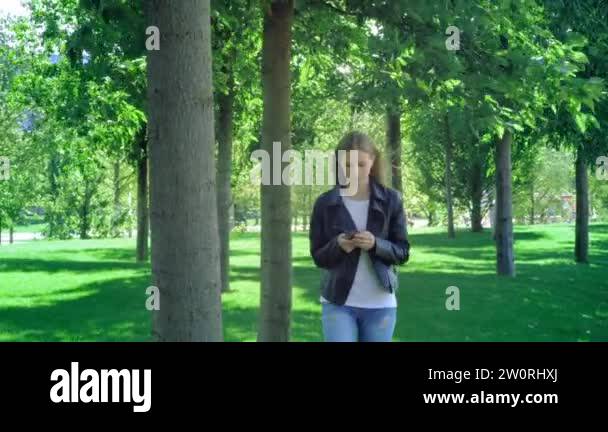 Front view of a perplexed woman walking checking smart phone content and then stops looking at ...