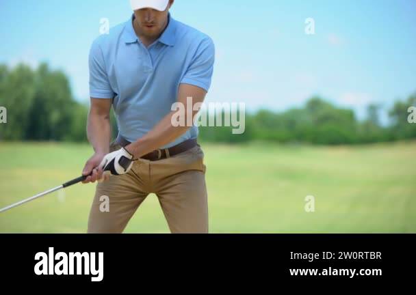 Young male golf player hitting ball, suffering terrible shoulder spasm ...