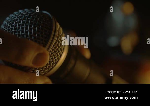 A hand is putting together a dynamic microphone in a half-light ...