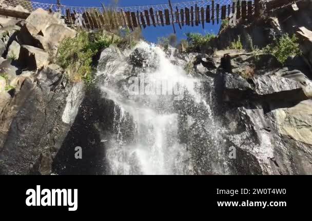 Simple wooden suspension bridge crossing over a tall waterfall in ...