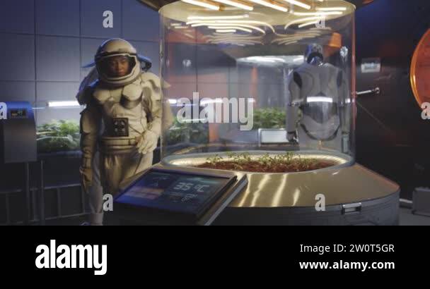 Astronauts and robot examining plant incubator Stock Video Footage - Alamy