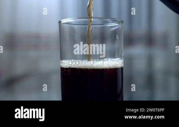 Blank glass beaker closeup pour dark soda, gas bubbles, camera motion ...