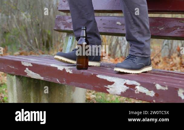 Beer bottle at a man's legs on the bench in the park Stock Video ...