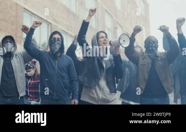 Caucasian young woman in hood screaming mottos in megaphone ...