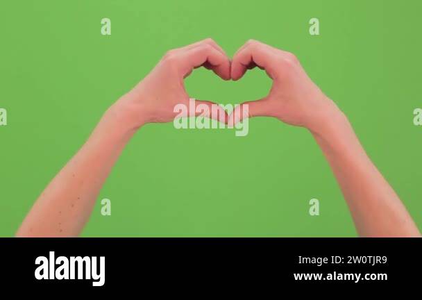 Closeup view of male hand making heart shape gesture isolated on green ...