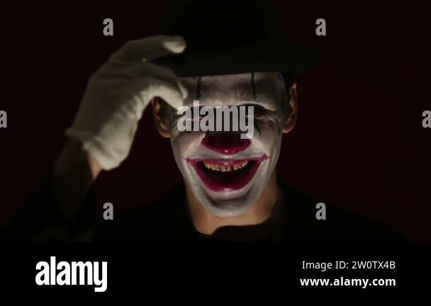 Terrible man in a clown makeup takes off his hat by welcoming his ...