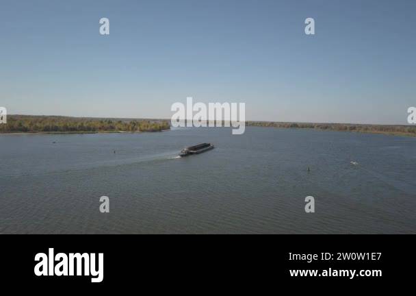 A tugboat ship pushes a barge upstream of the river to transport bulk ...
