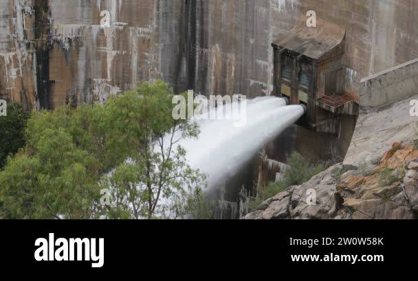 Shot of water being jet out of dam from enormous pipes. Water at high ...