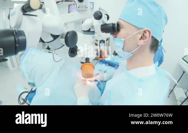 Surgeon looking into the microscope at the eye of female patient at the ...