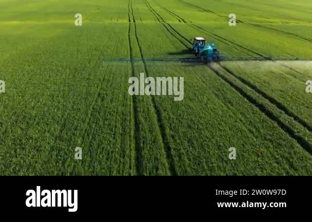 Aerial view of the tractor that irrigates the green field by special ...