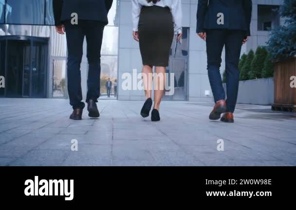 Rear back view feet of three successful business people commuting to ...