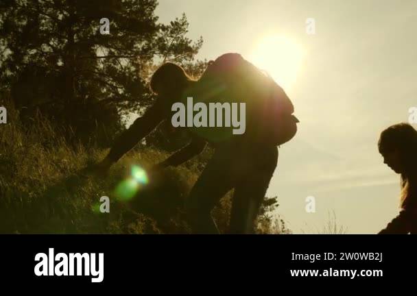 women travelers climb mountain, offer each other a helping hand ...