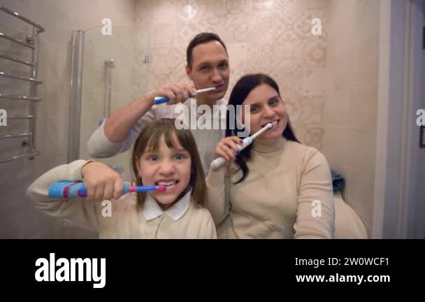 family brushing teeth, lovely little girl with parents with toothbrush ...