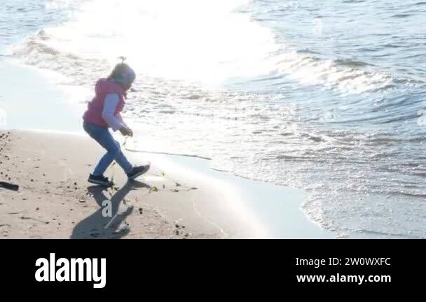 Cute little girl playing along sandy beach in slow motion. Little girl ...