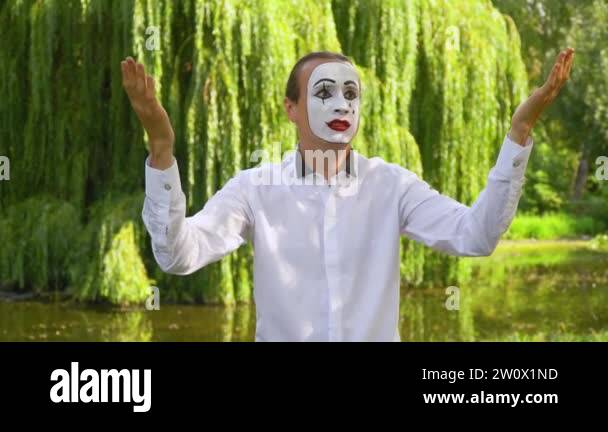 Mime on the park shows pantomime. Young funny mime behind an invisible ...