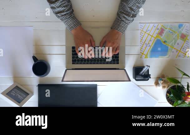 Male hands typing text on laptop keyboard at white wooden desk ...