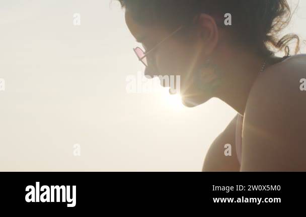 Close up side view of woman in sunglasses on white sky background ...