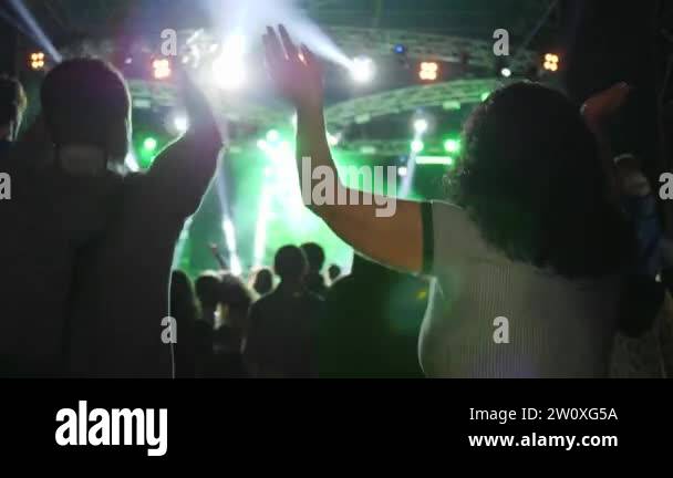 active youth with arms overhead clapping and jump before brightly lit ...