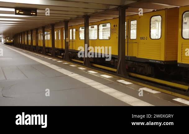 Two yellow trains in Berlin subway, arriving and leaving platform ...