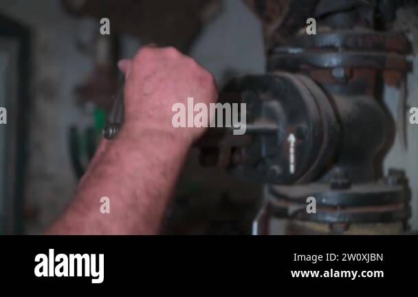 A man opens or closes a valve for entering gas or biofuels. Man in a ...