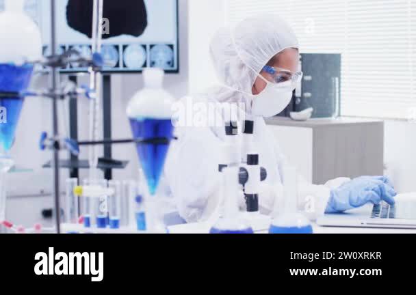 Female scientist typing formula on laptop and looking through ...