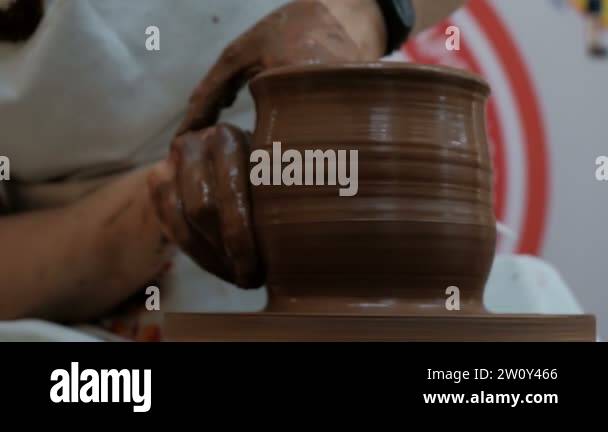 Potter shapes the clay product with pottery tools on the potters wheel ...