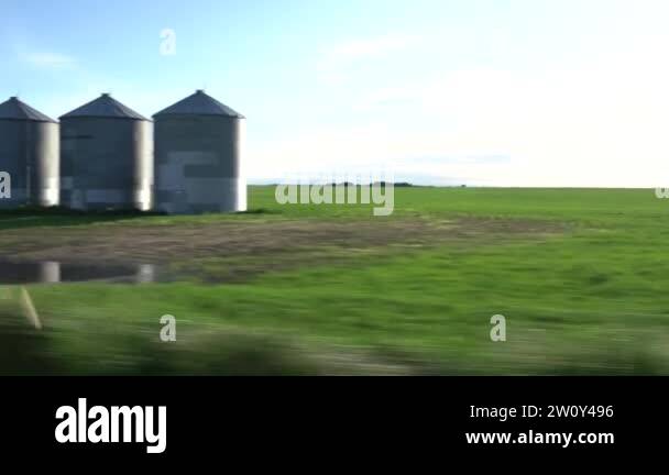 A drive by along recently planted fields with large metal grain silos ...