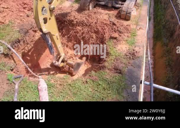 Backhoe works to repair broken water pipes from underground Stock Video ...