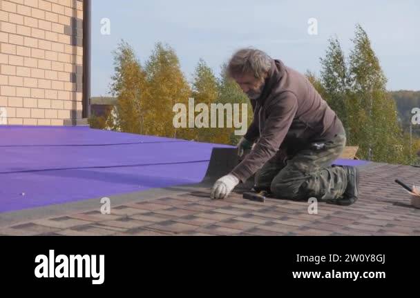 Laying a soft roof. Work at height. Laying a sheet of roofing material ...